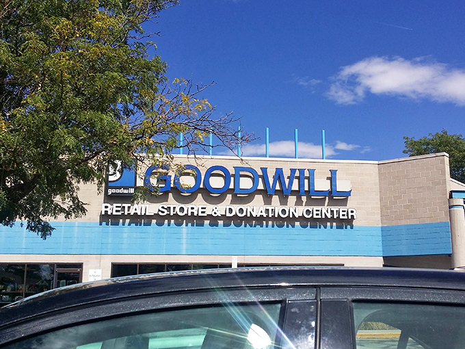 The iconic blue stripe of Aurora's Goodwill beckons like a retail lighthouse, guiding bargain hunters to shores filled with unexpected treasures.