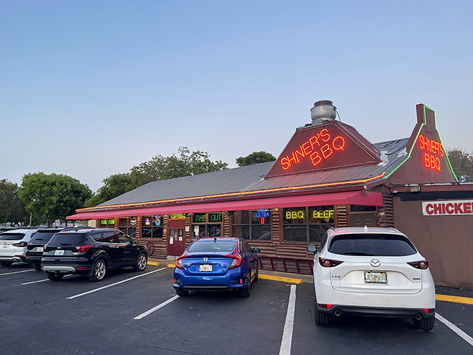 The neon beacon of Shiver's BBQ glows like a barbecue lighthouse, guiding hungry travelers to this unassuming Homestead treasure that's been perfecting smoke and fire for generations.