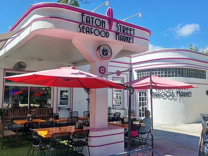 The pink Art Deco facade of Eaton Street Seafood Market stands like a retro postcard come to life, promising seafood treasures under those cheerful red umbrellas.