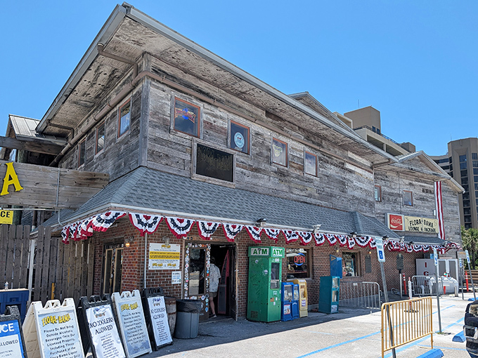 The weathered wooden exterior of Flora-Bama stands proudly at the state line, a testament to coastal resilience and good times that refuses to be washed away.