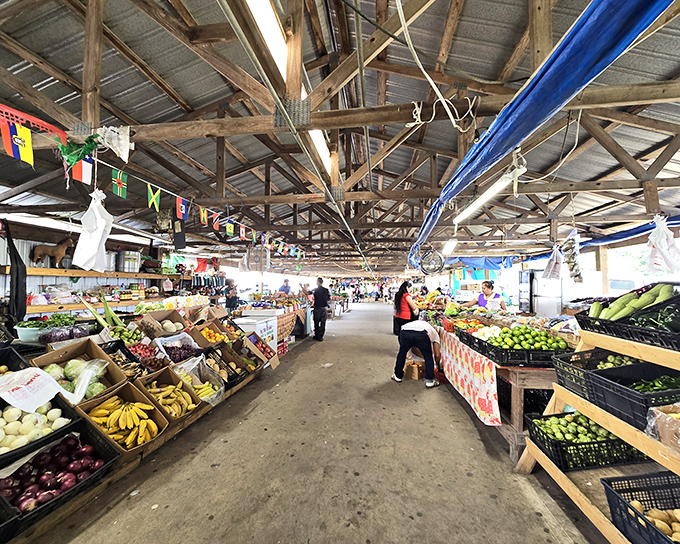 Fresh produce heaven awaits under rustic wooden beams, where colorful fruits and vegetables create a farmer's market within the flea market.