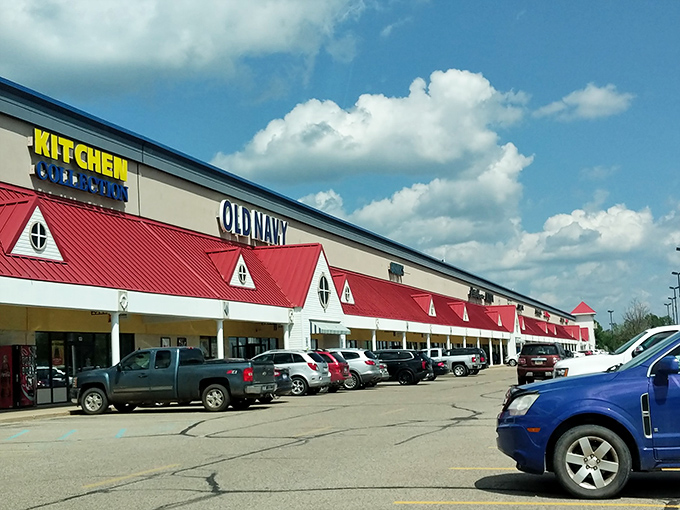 The iconic red-roofed fa&ccedil;ade of West Branch Outlet Mall stands like a beacon of bargains under Michigan's big sky. Shopping paradise awaits!