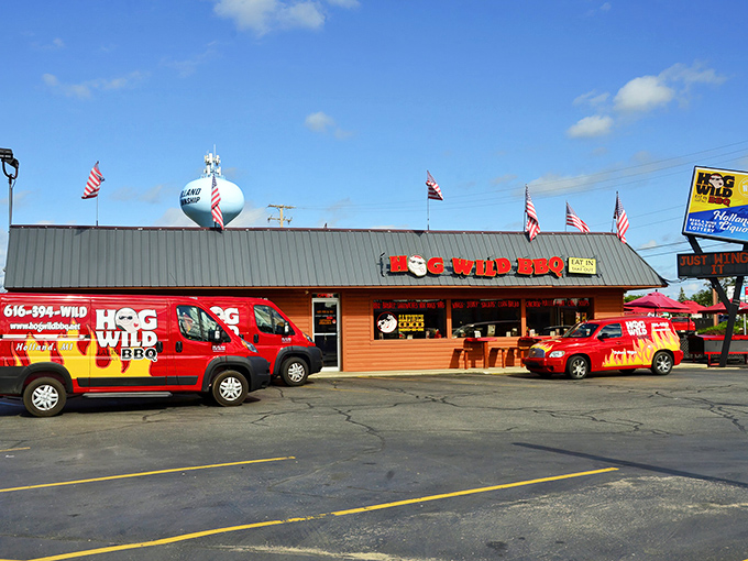 The unmistakable red signage of Hog Wild BBQ stands out like a beacon to hungry travelers, with American flags proudly waving above this Holland treasure.