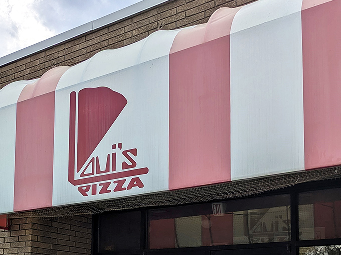 The bold red-and-white striped awning and glowing logo of Loui&rsquo;s Pizza stand as a welcoming beacon in Hazel Park, guiding the pizza-deprived straight to cheesy salvation.