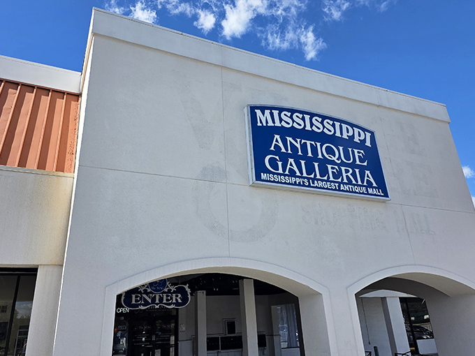 The white facade of Mississippi Antique Galleria stands like a portal to the past, promising treasures within that no online shopping cart could ever deliver.