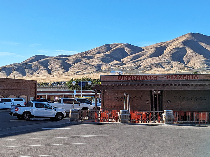The classic brick exterior of Winnemucca Pizzeria, where wooden lattice creates a mesmerizing shadow play on the outdoor patio.