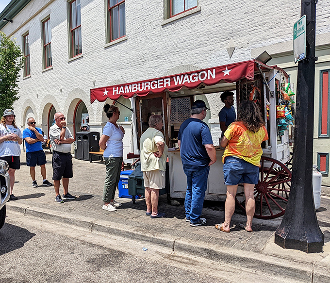 The iconic red awning of Hamburger Wagon stands like a culinary lighthouse on Miamisburg's brick streets, beckoning hungry pilgrims to its simple yet legendary offerings.