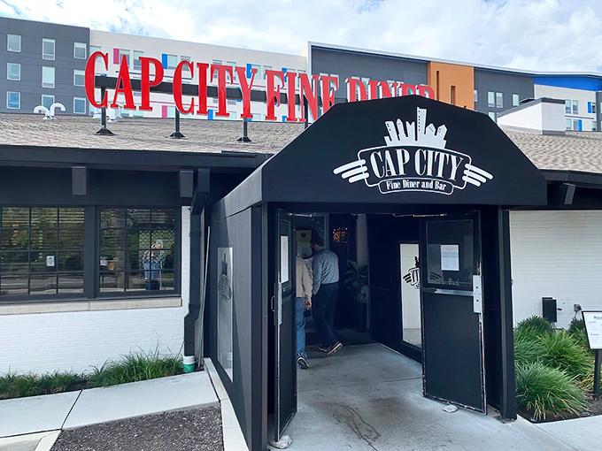 The iconic red Cap City sign glows like a beacon for hungry souls, promising comfort food with a sophisticated twist in Columbus.