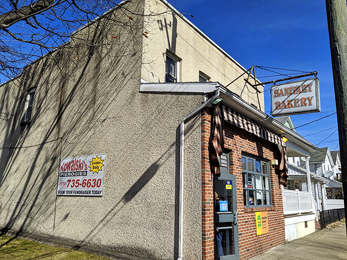 The unassuming exterior of Sanitary Bakery in Nanticoke, where culinary magic happens behind that modest brick fa&ccedil;ade and vintage sign.