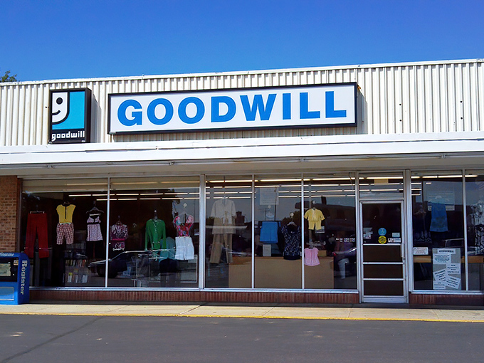 The iconic blue and white Goodwill sign beckons bargain hunters like a retail lighthouse on Main Avenue, promising treasures waiting to be discovered inside.