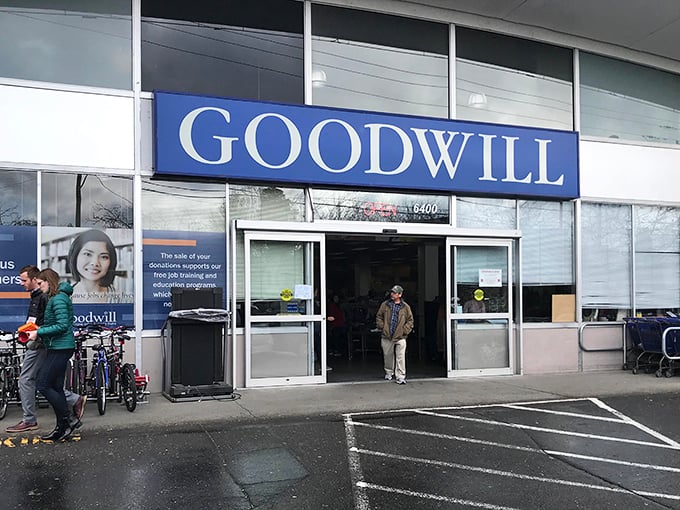 The iconic blue Goodwill sign beckons bargain hunters like a retail lighthouse. Seattle's notorious drizzle can't dampen the thrill of what treasures await inside.