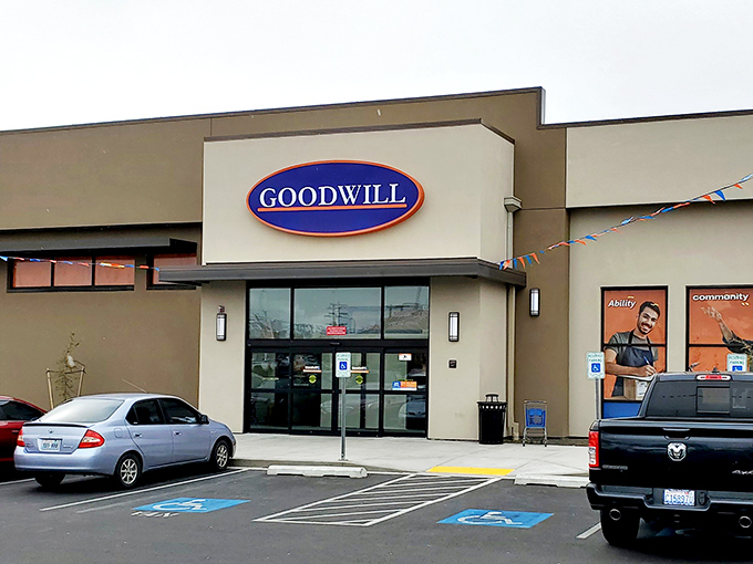 Morning light catches the Goodwill fa&ccedil;ade, where colorful pennant flags flutter like they're celebrating the deals waiting inside.