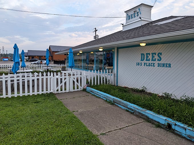 The classic white picket fence and vibrant blue umbrellas welcome you to Dee's 50's Place Diner&mdash;where nostalgia isn't manufactured, it's preserved.