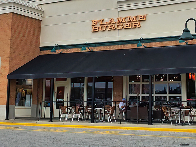 The iconic Flamme Burger storefront beckons with its golden signage and inviting patio &ndash; like a culinary lighthouse guiding hungry souls to flavor paradise.