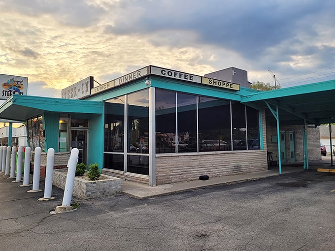 The turquoise time capsule beckons at dusk, its mid-century charm promising comfort food that'll transport you back to simpler times.