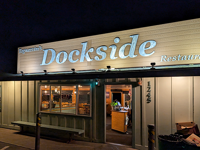 Tognazzini's Dockside glows like a beacon for seafood lovers after dark, promising maritime delights within its unassuming coastal exterior.