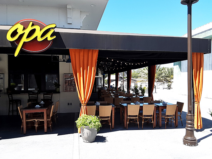 The "Opa" sign welcomes you, while the curtains hint at the flavorful Mediterranean feast waiting inside.