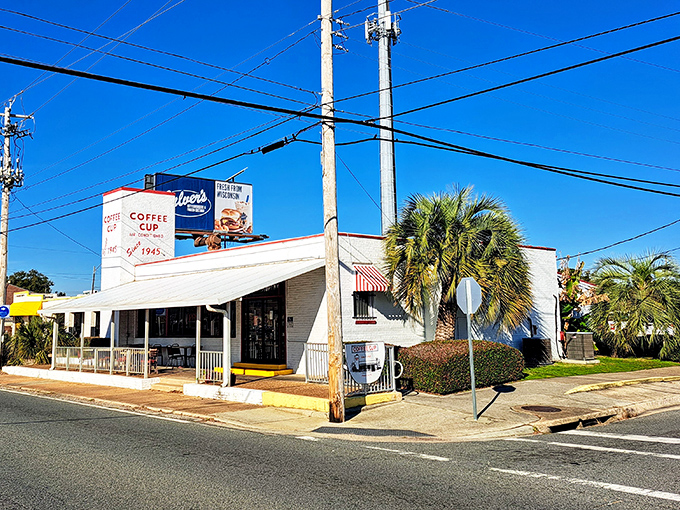 The unassuming white exterior of Coffee Cup Restaurant stands as a time capsule of Americana, where Florida palm trees meet classic diner culture.