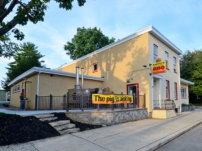 The unassuming yellow exterior of Harvey's Main Street BBQ with its "The pig is cooking" banner – a siren call to barbecue lovers everywhere.