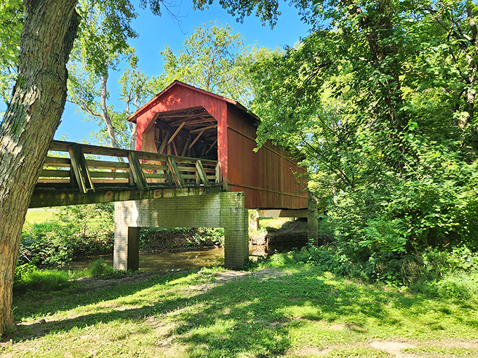 The classic red exterior of Sugar Creek Covered Bridge stands proudly against Illinois greenery, like a Norman Rockwell painting come to life.