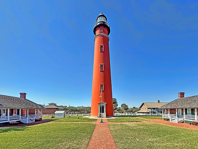 The brick-red tower reaches toward a perfect blue Florida sky, with a symmetrical pathway inviting visitors to begin their 203-step adventure.