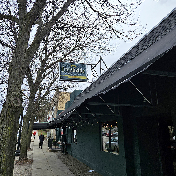 The Creekside sign hangs like a beacon of comfort food promise, framed by bare winter branches that only make the warm glow inside more inviting.