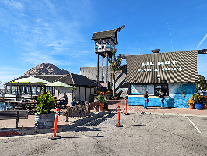 Harbor Hut's distinctive silhouette welcomes hungry travelers like a lighthouse for seafood lovers, complete with palm trees swaying in the ocean breeze and Morro Rock standing guard.