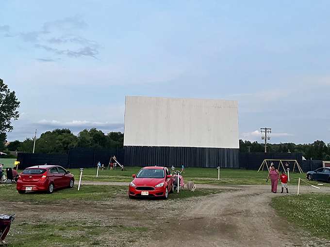 The iconic white screen of Magic City Drive-In stands ready for dusk, when movie magic transforms this humble field into an outdoor cinema paradise.