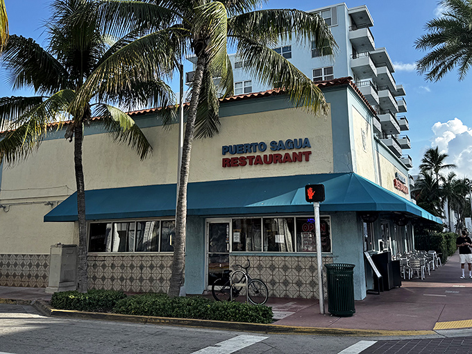 Miami Beach's culinary time capsule stands proudly under swaying palms, its blue awning a beacon for sandwich pilgrims seeking Cuban perfection.