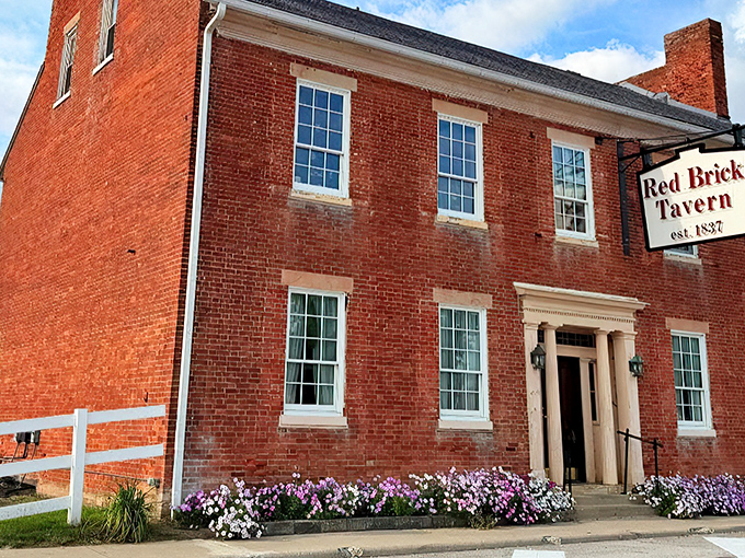 The iconic Red Brick Tavern stands proudly along the National Road, its vibrant flower beds adding a splash of color to nearly two centuries of American history.