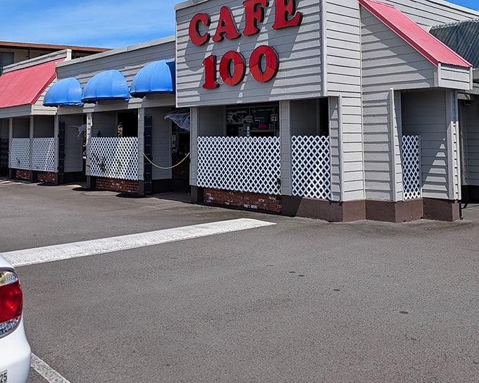 The unassuming exterior of Cafe 100 with its bright red signage and blue awnings&mdash;proof that culinary treasures often hide in plain sight.