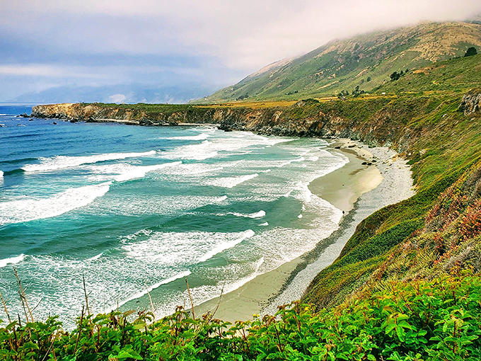 Nature's perfect crescent: Sand Dollar Beach curves gracefully along Big Sur's coastline, a half-mile stretch of golden sand embraced by dramatic cliffs.