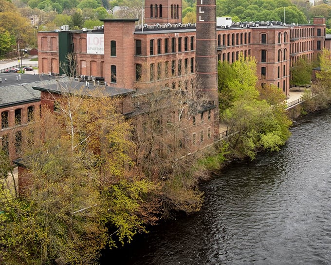 Historic brick mills stand sentinel along Cumberland's waterways, where industrial heritage meets natural beauty in perfect New England harmony.