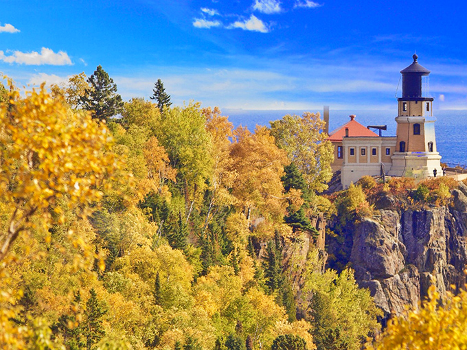 Nature's perfect frame: autumn's golden embrace cradles this iconic lighthouse perched dramatically on Minnesota's rocky North Shore. Mother Nature showing off her interior design skills.