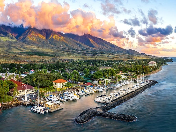 Lahaina Harbor at sunset, where boats rest peacefully against a backdrop of West Maui Mountains painted in golden light. Nature's perfect postcard moment.
