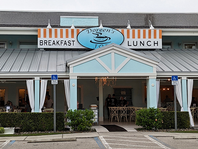The cheerful blue exterior of Doreen's Cup of Joe beckons like a breakfast lighthouse on Marco Island, promising morning salvation under that iconic striped awning.