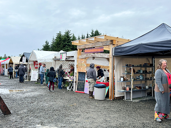 Handcrafted treasures line the gravel paths at Homer Farmers Market, where Alaska's bounty meets artisan craftsmanship under the watchful gaze of spruce sentinels.