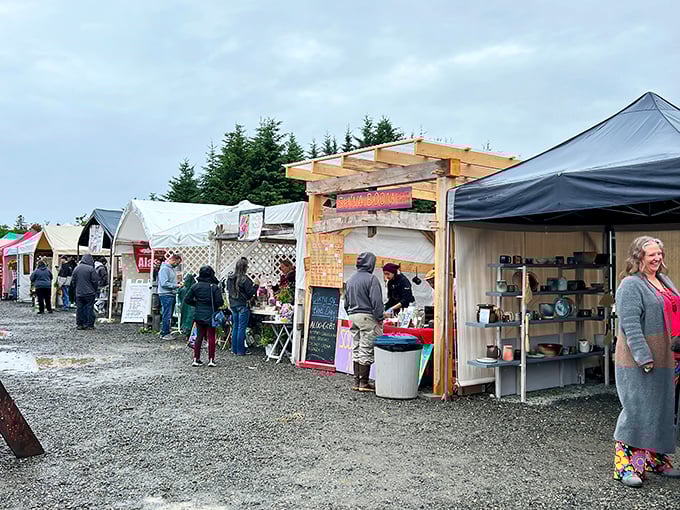 Handcrafted treasures line the gravel paths at Homer Farmers Market, where Alaska's bounty meets artisan craftsmanship under the watchful gaze of spruce sentinels.