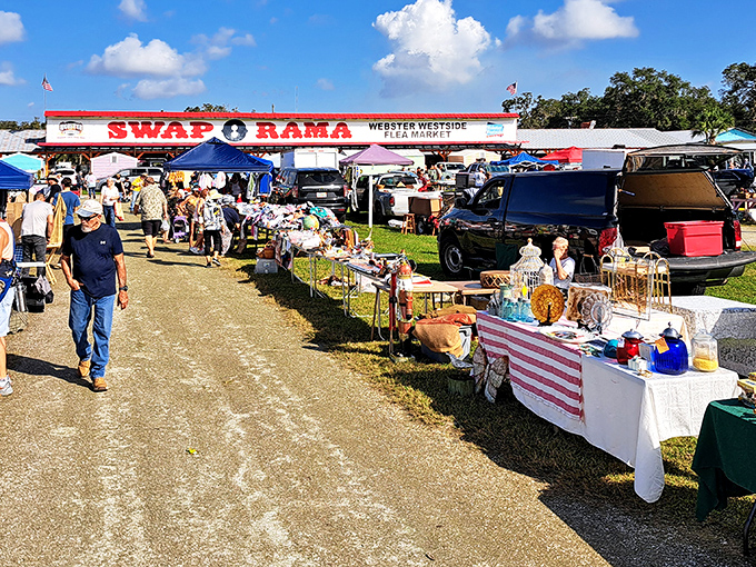 The iconic Swap-O-Rama sign stands like a technicolor beacon against Florida's blue sky, promising treasures beneath those candy-colored vendor sheds.