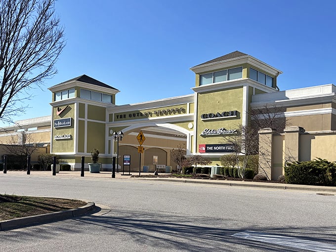 The grand entrance beckons with promises of designer treasures at mortal prices. Coach, Eddie Bauer, and The North Face logos hint at the bargains waiting inside.