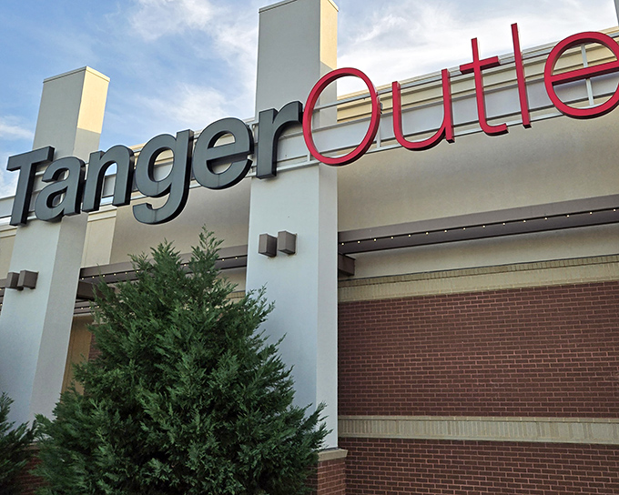 The iconic Tanger Outlets sign welcomes bargain hunters like a retail promised land. Modern architecture meets shopping paradise under the Texas sky.