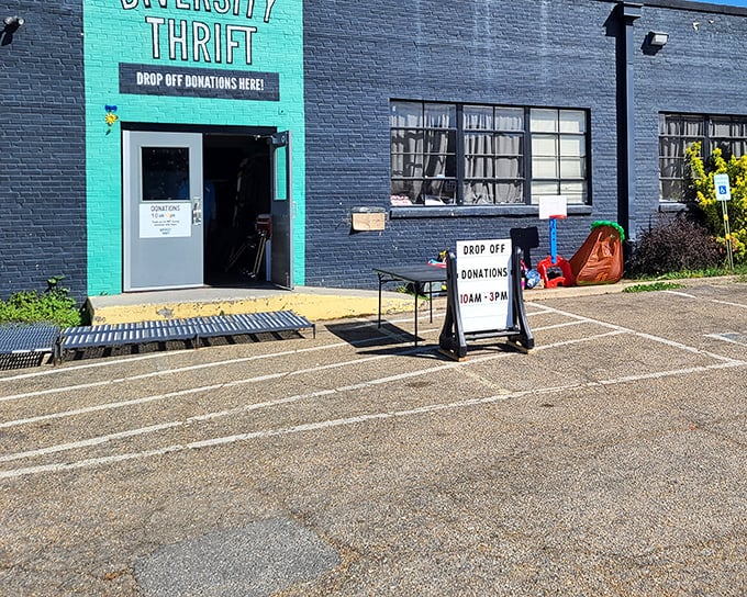 The unmistakable teal entrance to Diversity Thrift stands out against the navy blue building, beckoning bargain hunters with promises of hidden treasures inside.