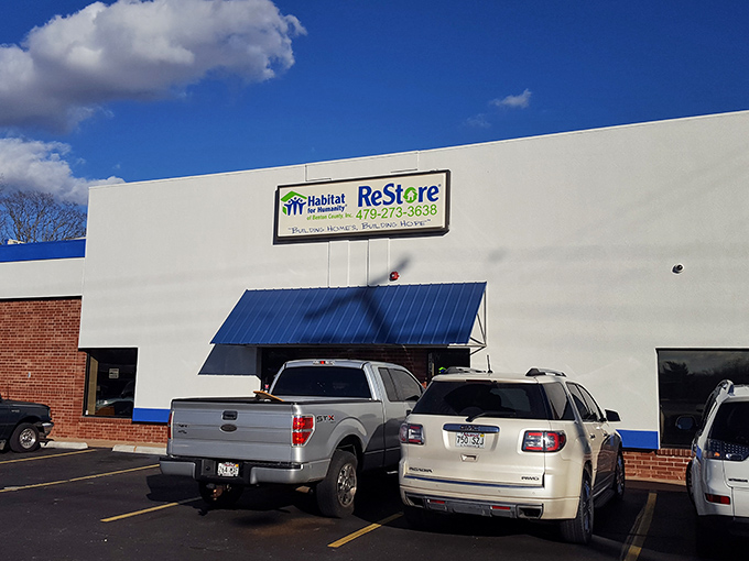 The ReStore&rsquo;s exterior features a bright blue sign and a parking lot filled with cars, inviting you to explore their furniture section full of pieces that whisper, &ldquo;I&rsquo;ve been loved, but I&rsquo;ve got plenty more to give.