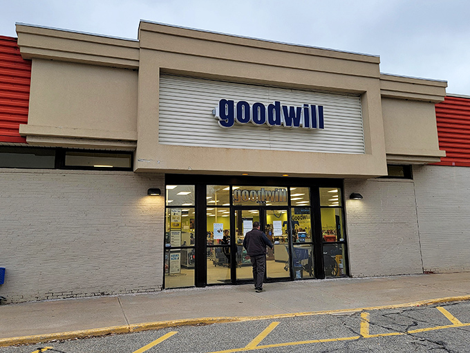 The iconic blue Goodwill sign beckons like a lighthouse for bargain hunters. Inside those doors, treasure awaits for the patient and the bold.