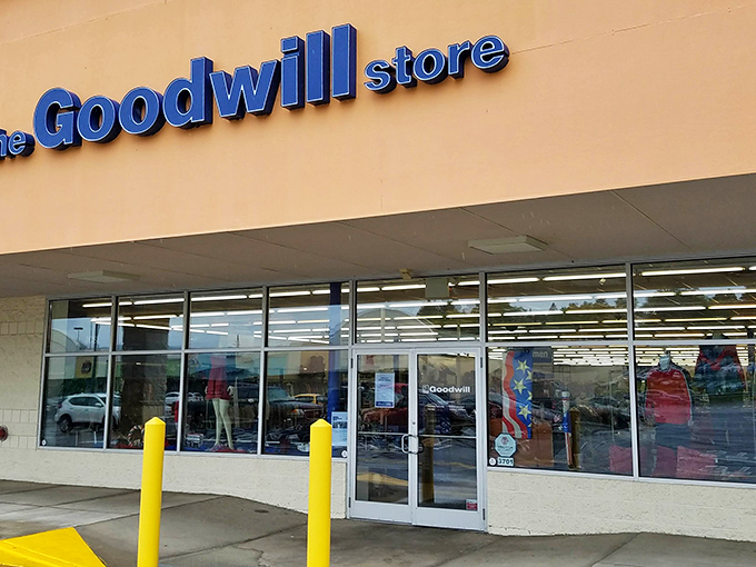 The blue Goodwill sign beckons like a lighthouse for bargain hunters. Behind these unassuming doors, fashion treasures await discovery.