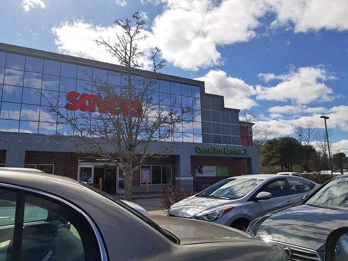 The gleaming glass facade of Savers beckons like a siren song to bargain hunters under Rhode Island's brilliant blue skies.