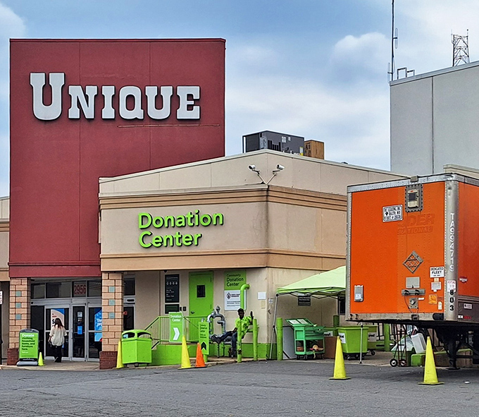The bold red UNIQUE sign beckons like a siren call to thrift enthusiasts, while the lime-green donation center stands ready to receive tomorrow's treasures.
