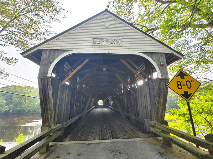 The historic Blair Covered Bridge welcomes travelers with its weathered charm and distinctive architecture, a wooden time portal spanning the Pemigewasset River.