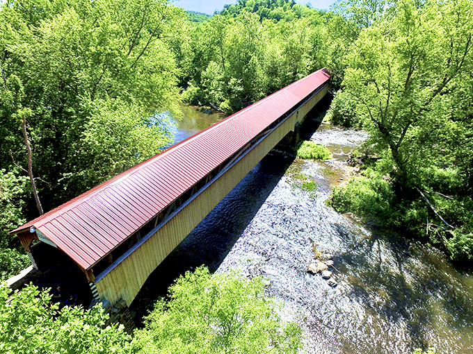 Like a rustic runway for time travelers, this 270-foot wooden marvel stretches across Tuscarora Creek, its red roof a beacon among Pennsylvania's lush greenery.