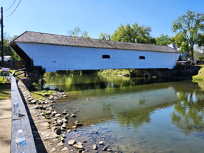 The Elizabethton Covered Bridge gleams like a pristine white bookmark between chapters of Tennessee history, its reflection doubling the visual magic.